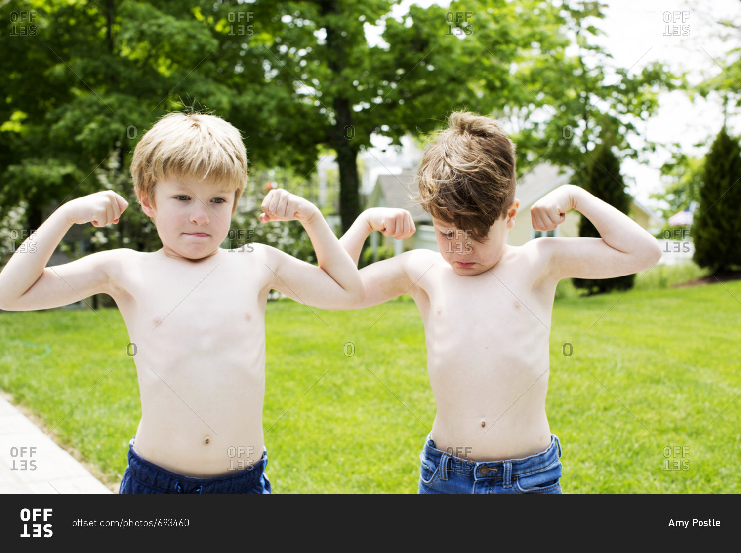 Two kids flexing their muscles outside stock photo - OFFSET