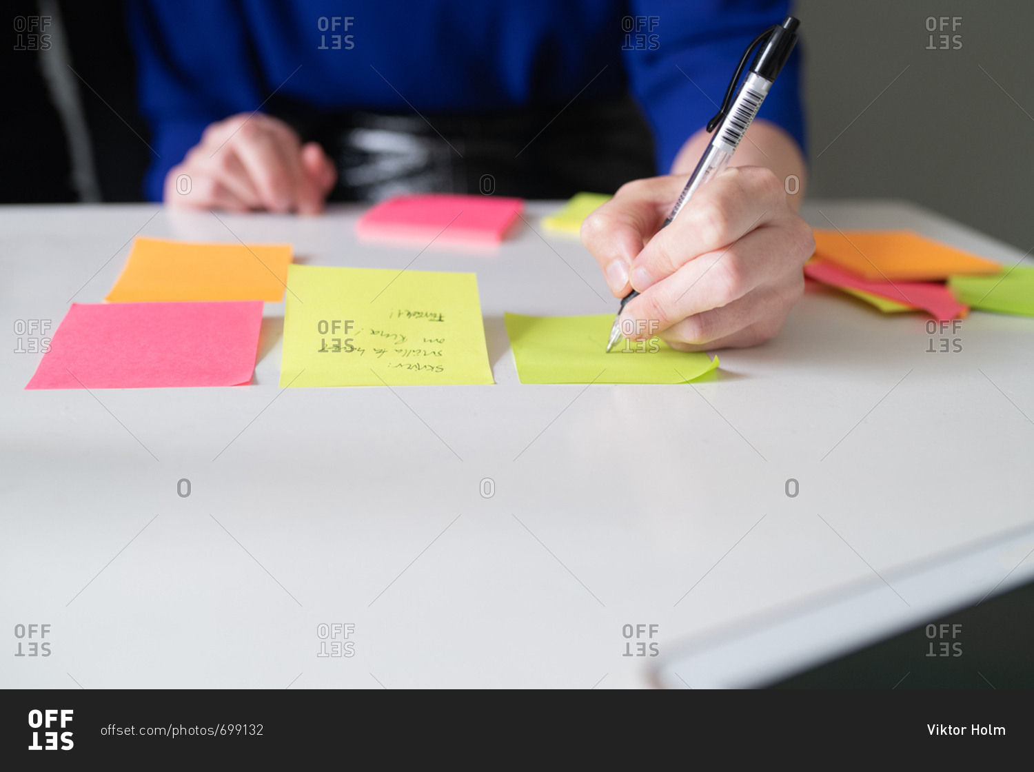 Close up of woman's hand writing notes on sticky notes laid out on ...