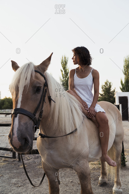Barefoot woman sitting bareback on horse stock photo - OFFSET