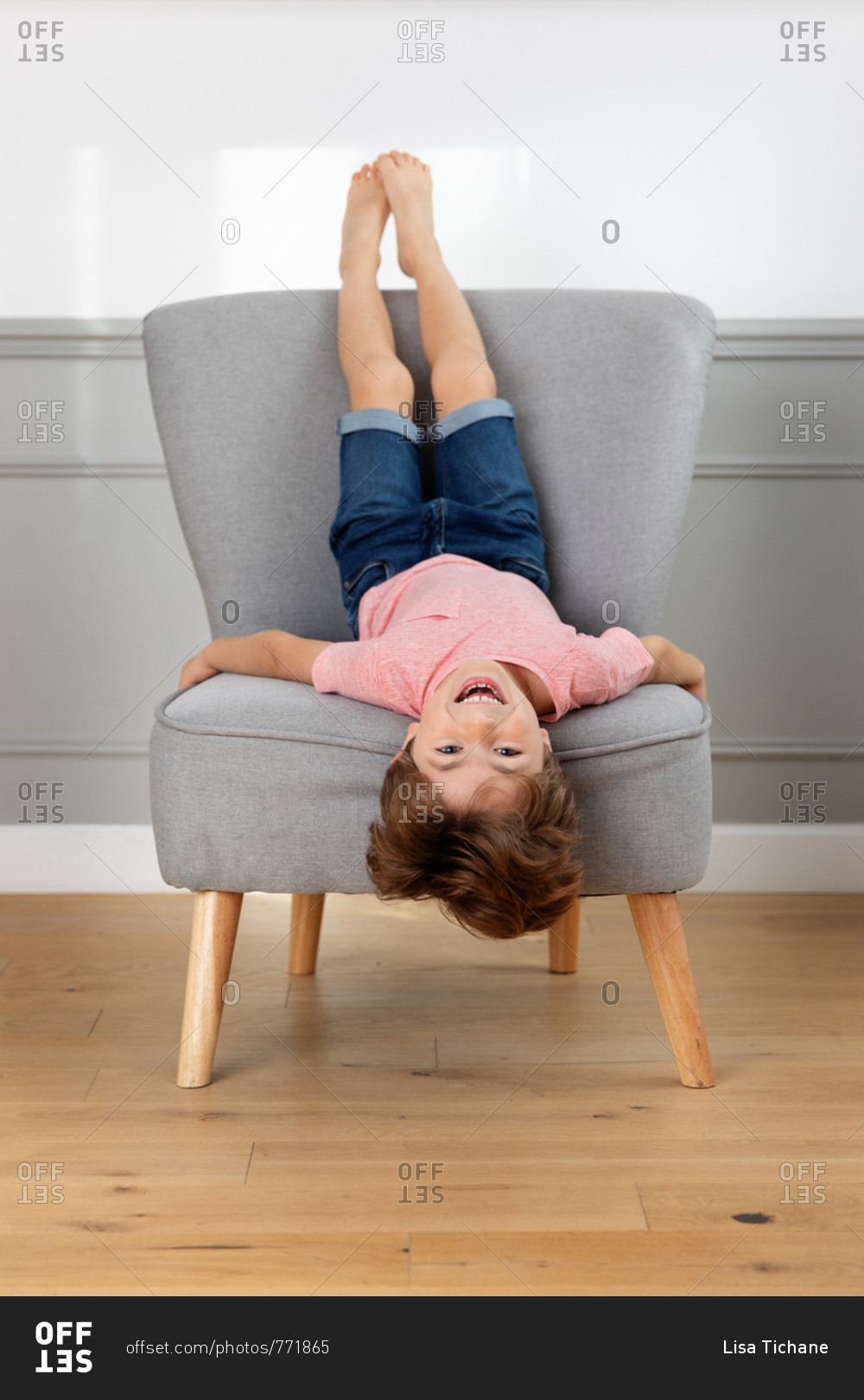 Laughing Boy Lying Upside Down On Chair Stock Photo OFFSET