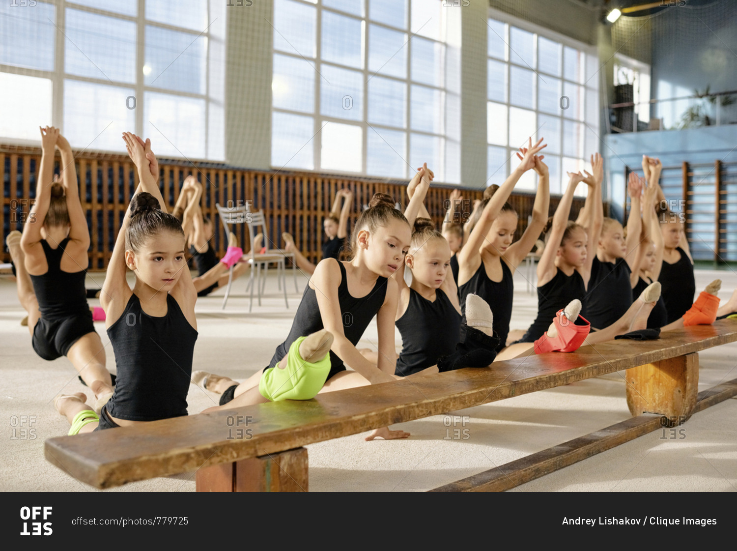 Group of little gymnasts doing splits near the bench with their hands ...