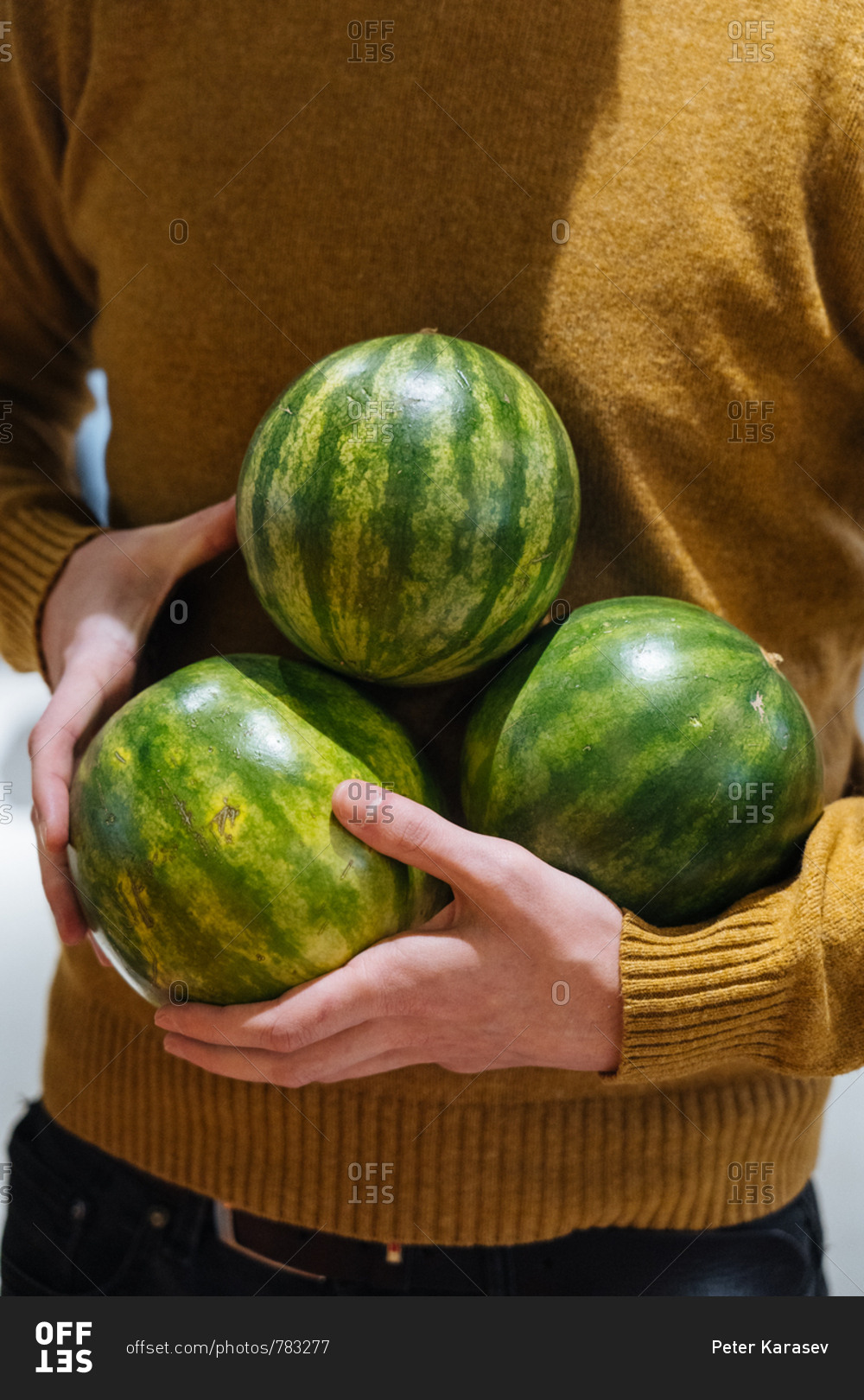 Man holding three small watermelons stock photo - OFFSET