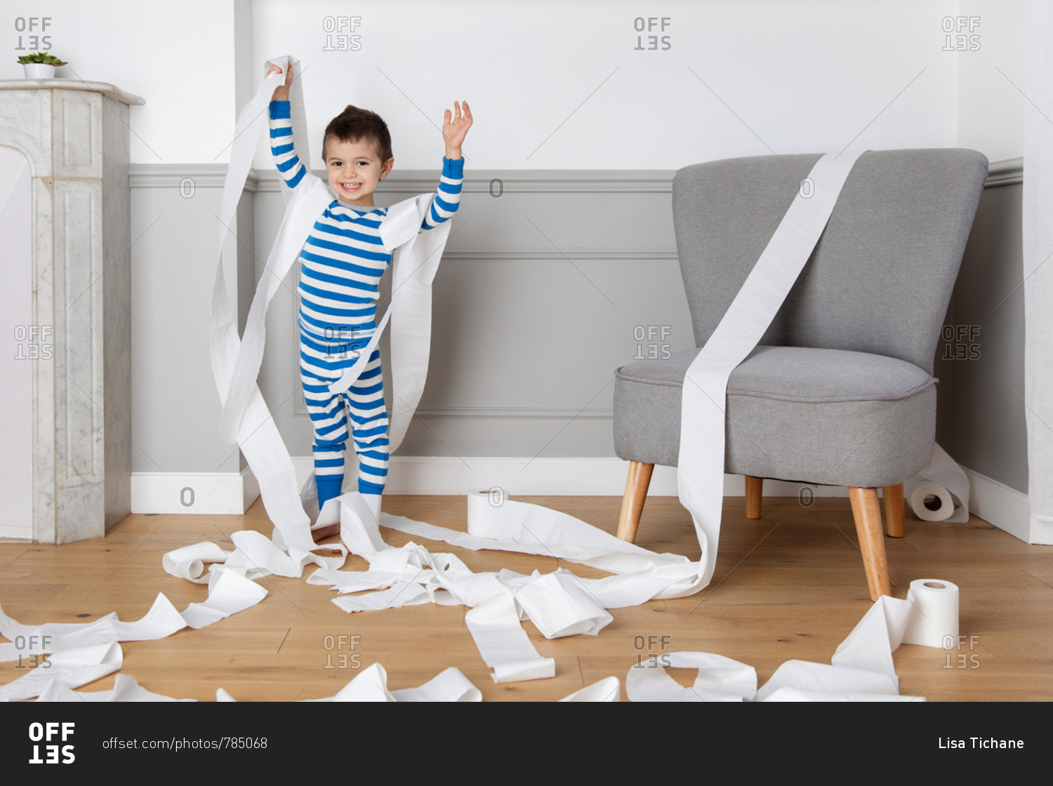 Young boy making a mess with rolls of toilet paper stock photo - OFFSET