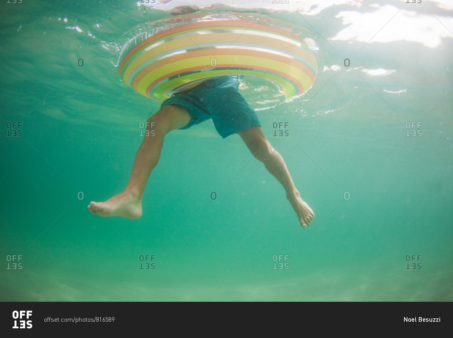 Underwater view of boy swimming in an inner tube in the ocean stock ...
