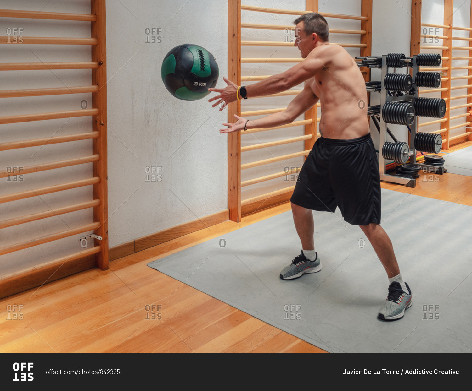 Powerful shirtless male throwing heavy ball against wall during fitness ...