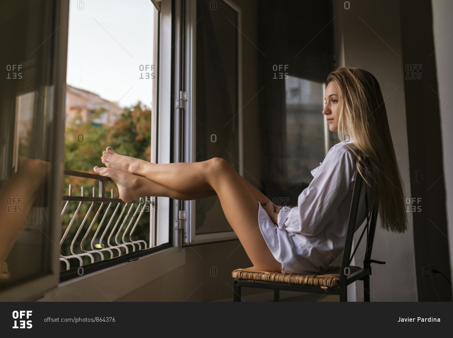 Attractive woman sitting with feet out of hotel room window stock photo ...