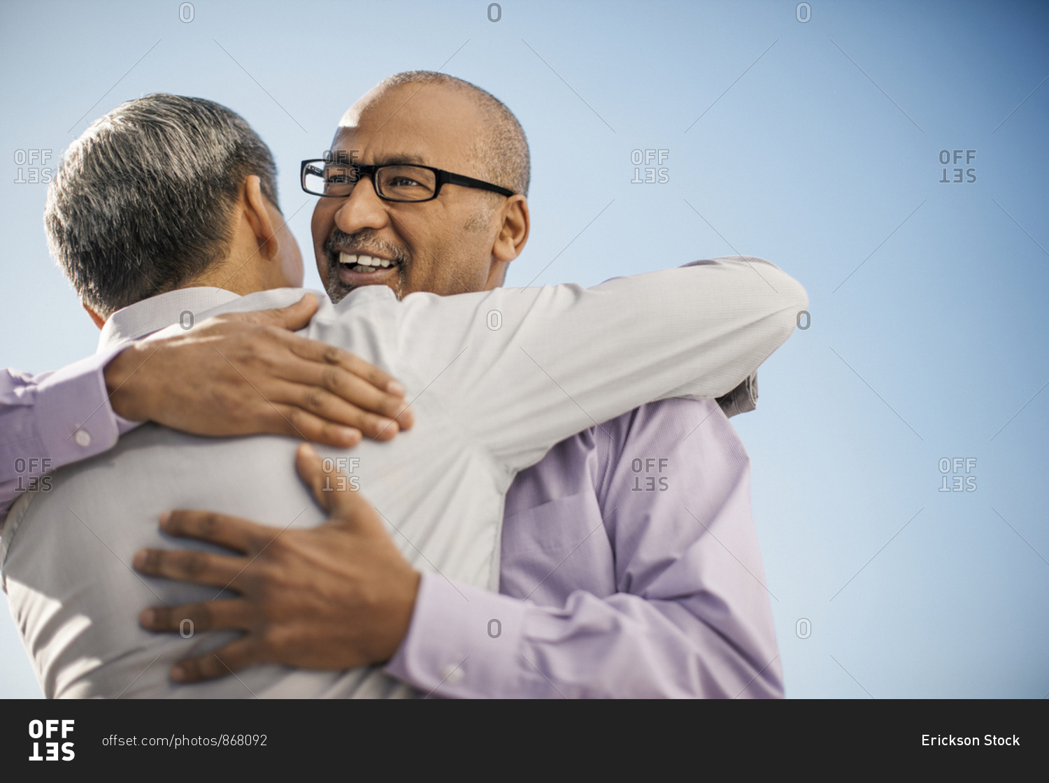Businessmen greeting each other with a hug. stock photo - OFFSET
