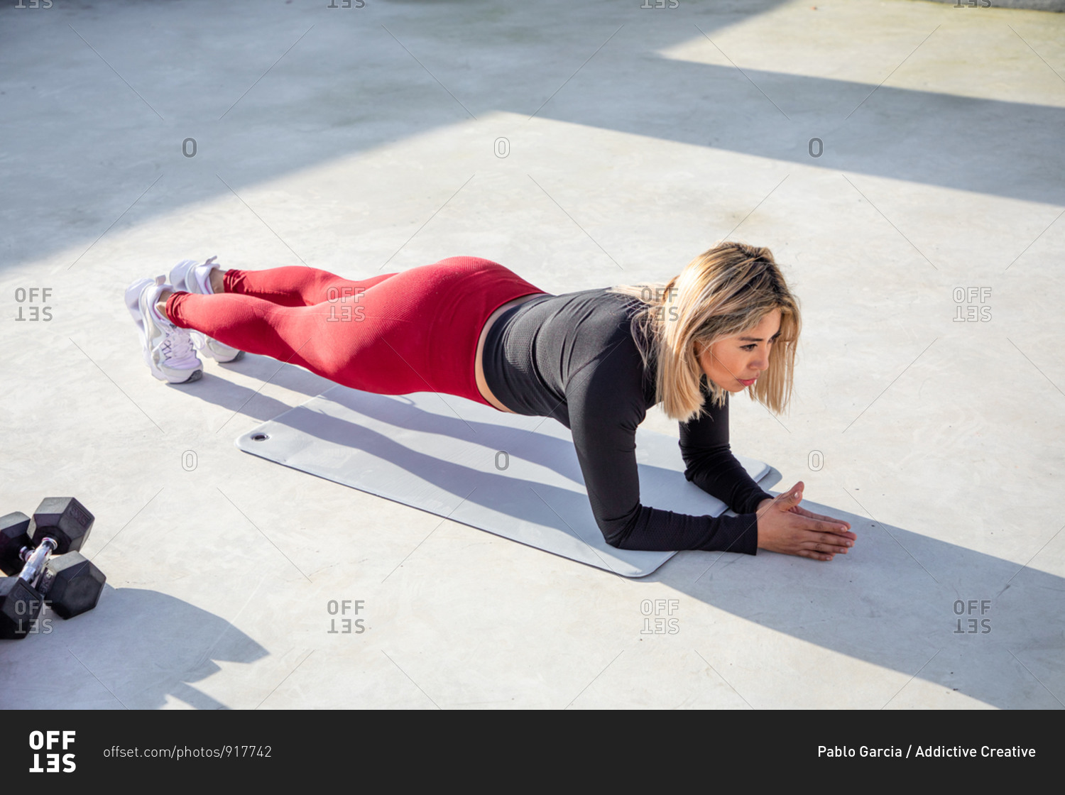 From above of young blonde in stylish active wear in plank position on ...