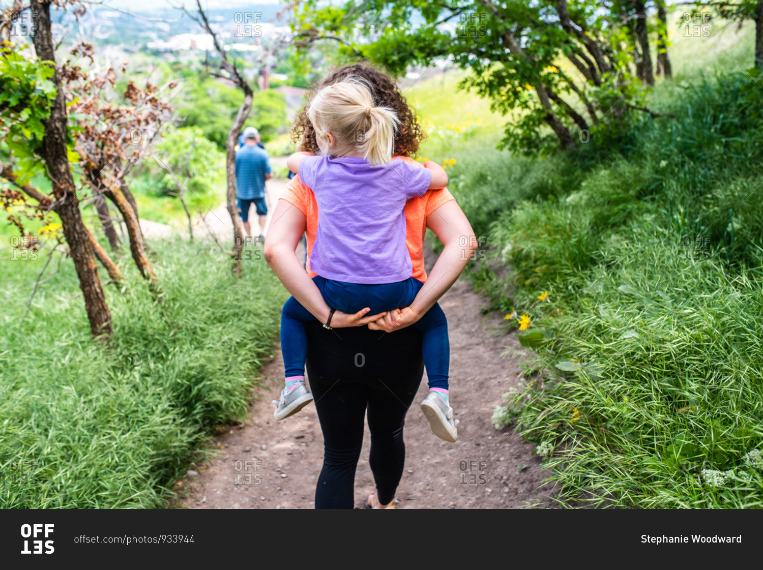 Piggyback ride down a path on a family hike stock photo - OFFSET