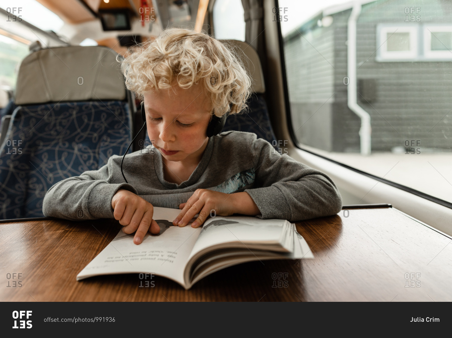 Young boy reading a book while riding on a train stock photo - OFFSET