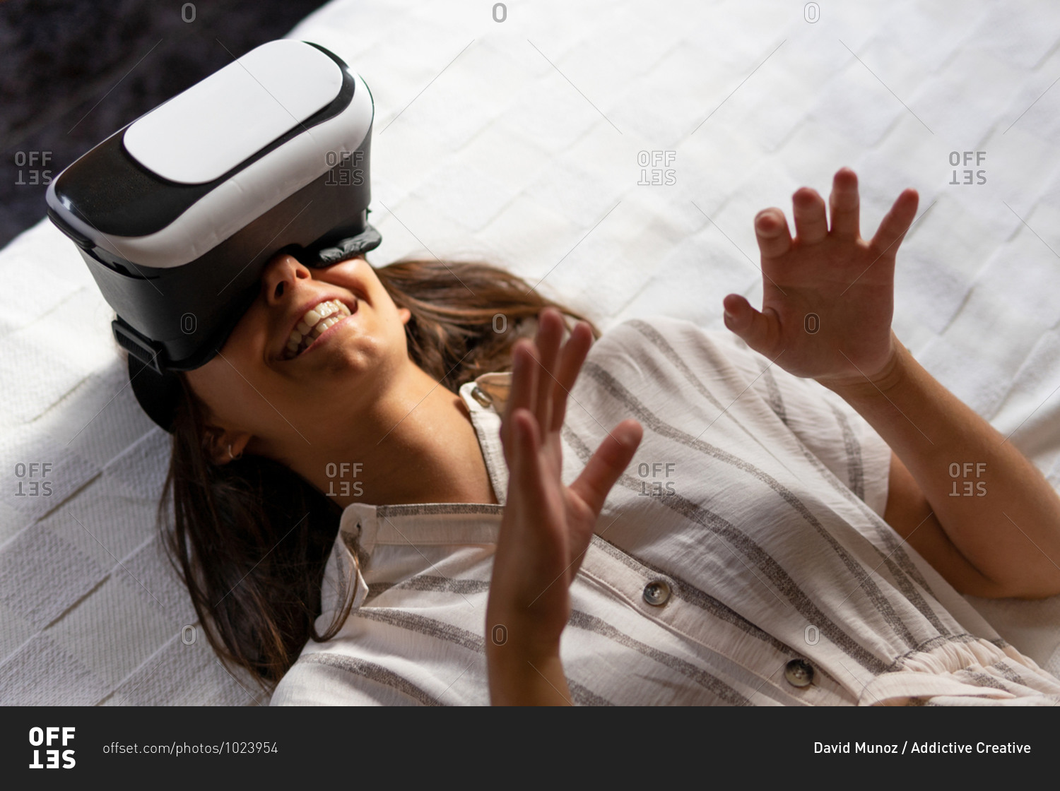From above happy young female in VR headset smiling and gesticulating ...