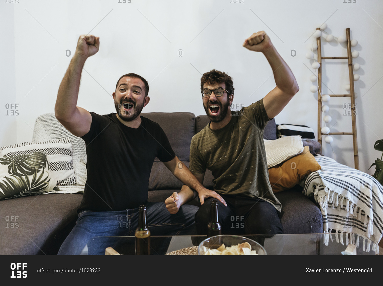 Cheerful male spectators screaming while watching sports in living room ...