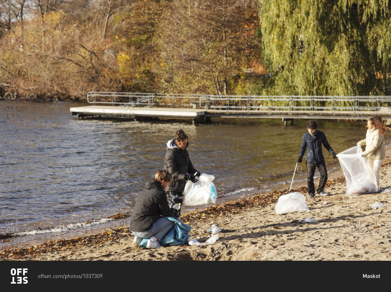 Male and female friends collecting plastic garbage by lake - Stock ...