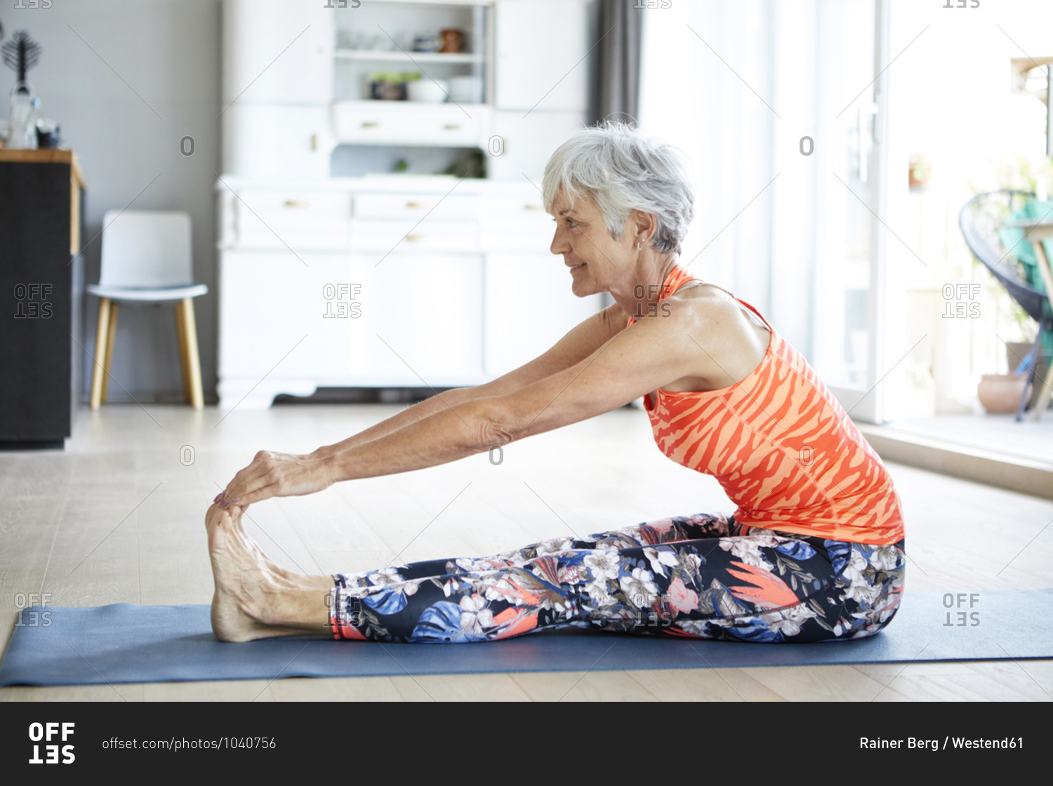 Fit Senior Woman Stretching Leg And Back While Exercising At Home Stock