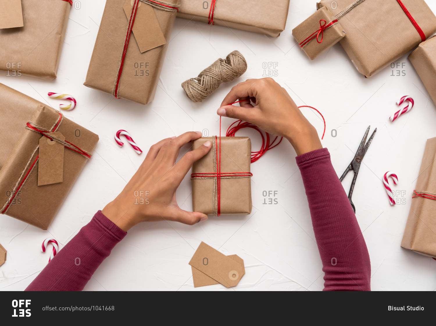 Female's hands wrapping Christmas gift boxes decorated with kraft paper ...