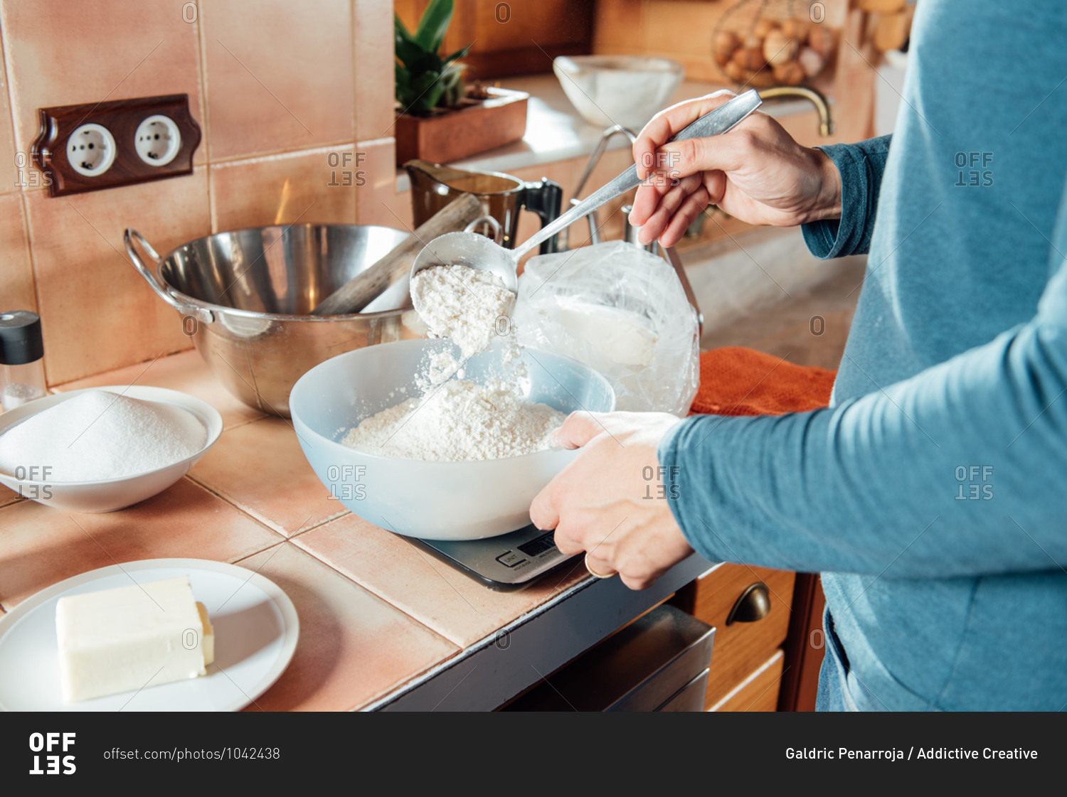 Crop anonymous male adding flour into bowl placed on scales while ...