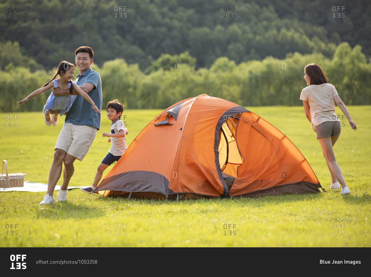 Happy young Chinese family camping outdoors stock photo - OFFSET