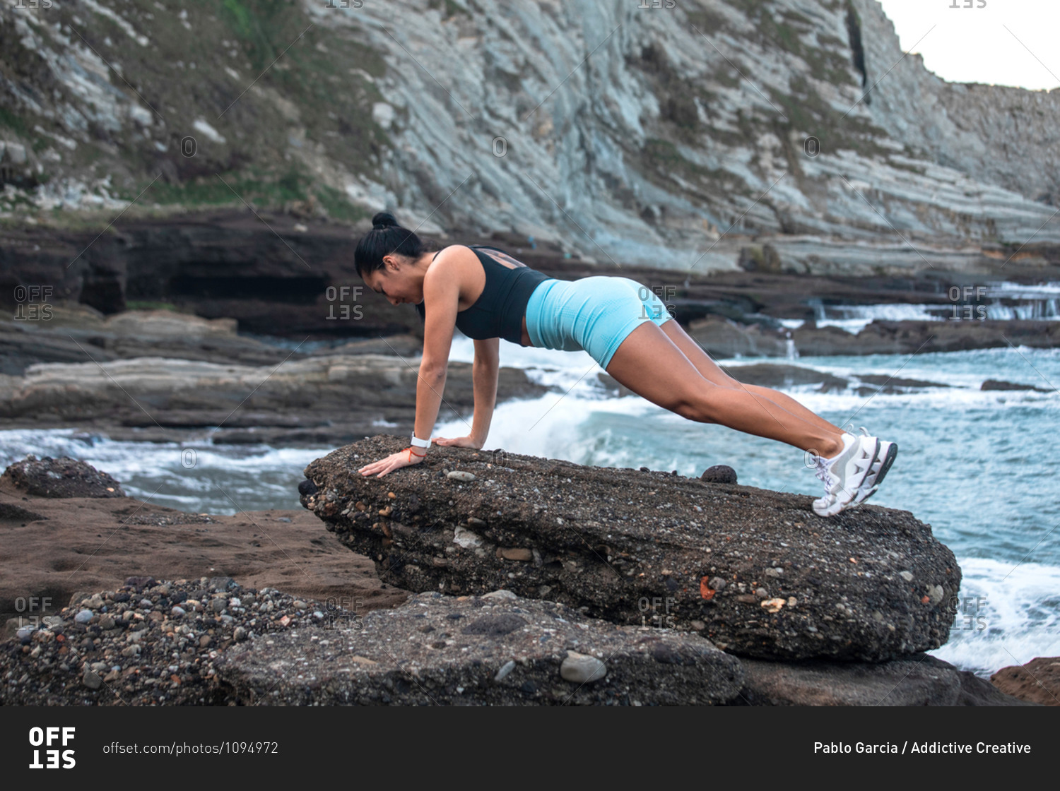 Side view of sporty female balancing in plank position during intense ...