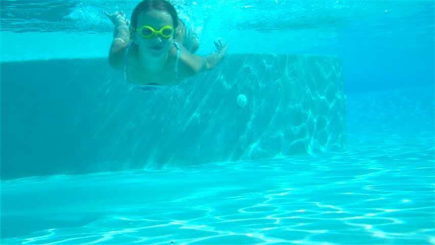 Smiling young boy without swim goggles swimming underwater in pool ...