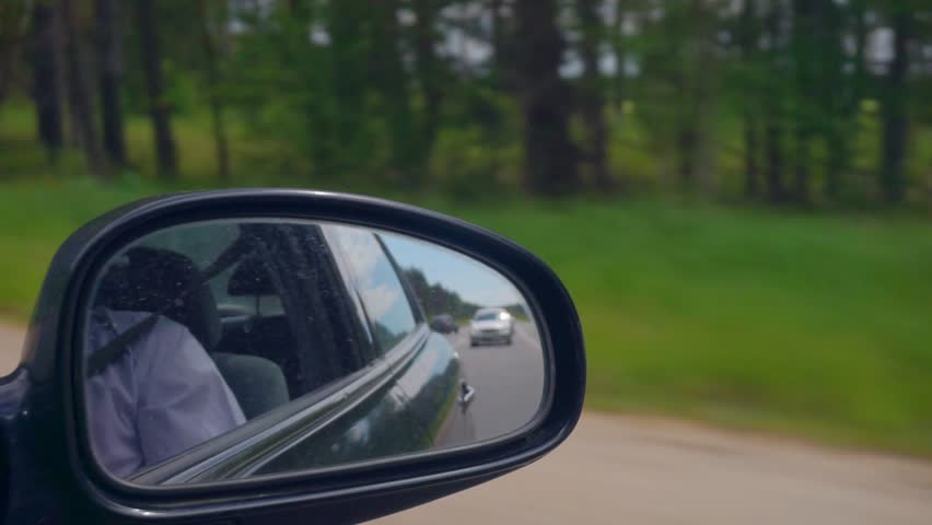 Red automobile in motion. View in the rear view side mirror of a auto ...
