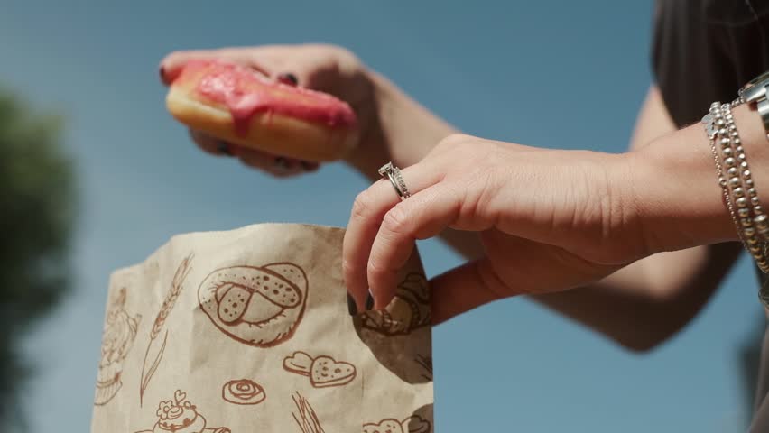 woman slowly pulls donut out paper Stock Footage Video (100% Royalty ...