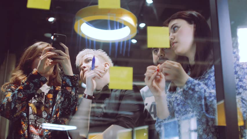 Young group of diverse people standing behind glass wall of office ...