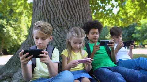 Children Playing Gadgets Sitting Under Tree Stock Footage Video (100% ...