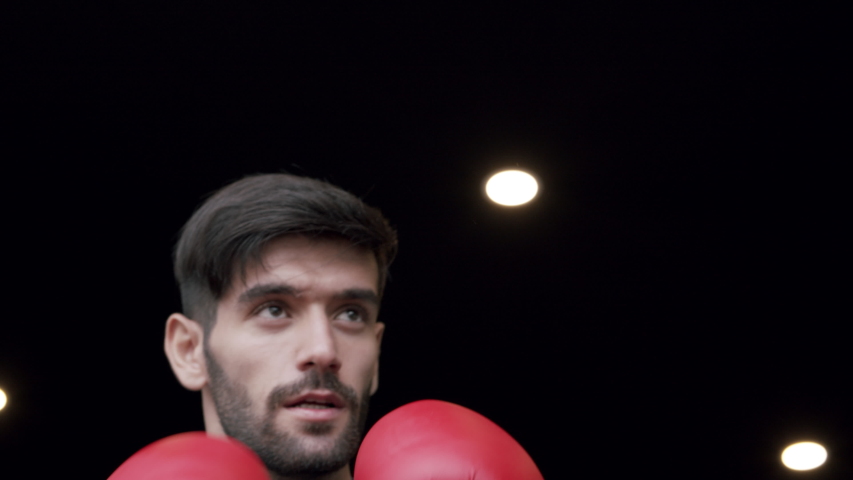 Portrait of young handsome Caucasian sweaty boxer in gloves leaning on ...