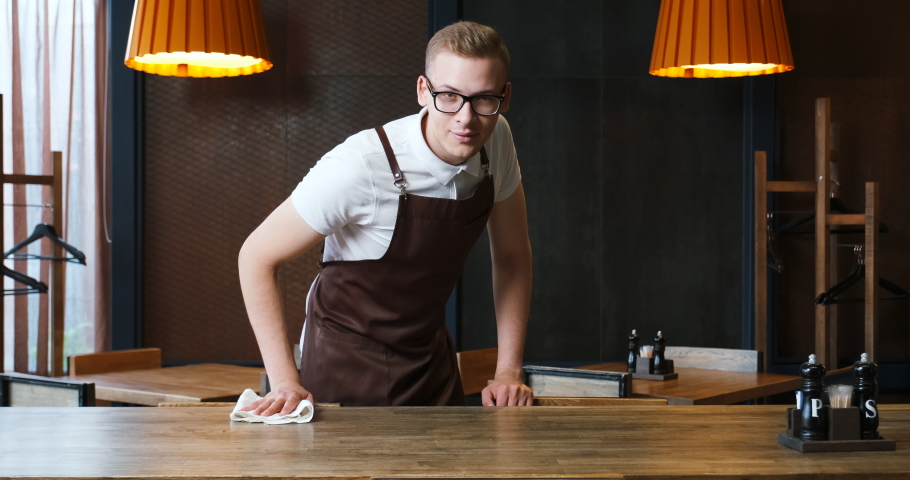 positive waiter restaurant cleaning table looks Stock Footage Video ...