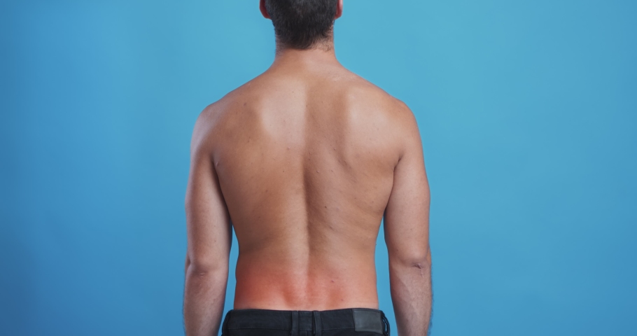 Adult man suffering from back pain standing on green screen background ...