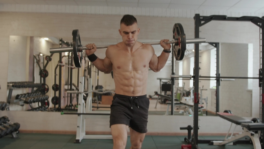 A sportive woman training in the gym - pulling the handles connected to ...