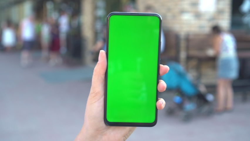 Close up hands woman holding phone with vertical green screen on busy ...