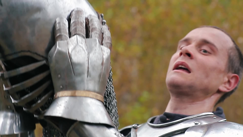 Legs knights in armor marching on the road against a white fence ...