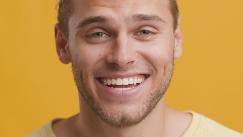 Portrait of silly young man making funny faces and laughing having fun looking at camera ...