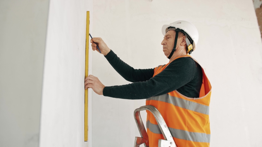 male worker checking level of the wall with the bubble level tool ...