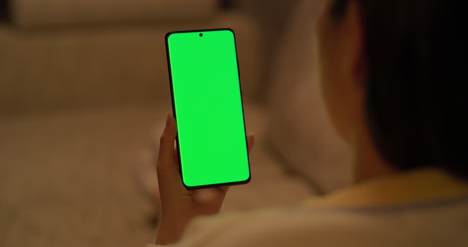 Beautiful Authentic Female Using a Smartphone with Green Screen Mock Up Display at Home Living ...
